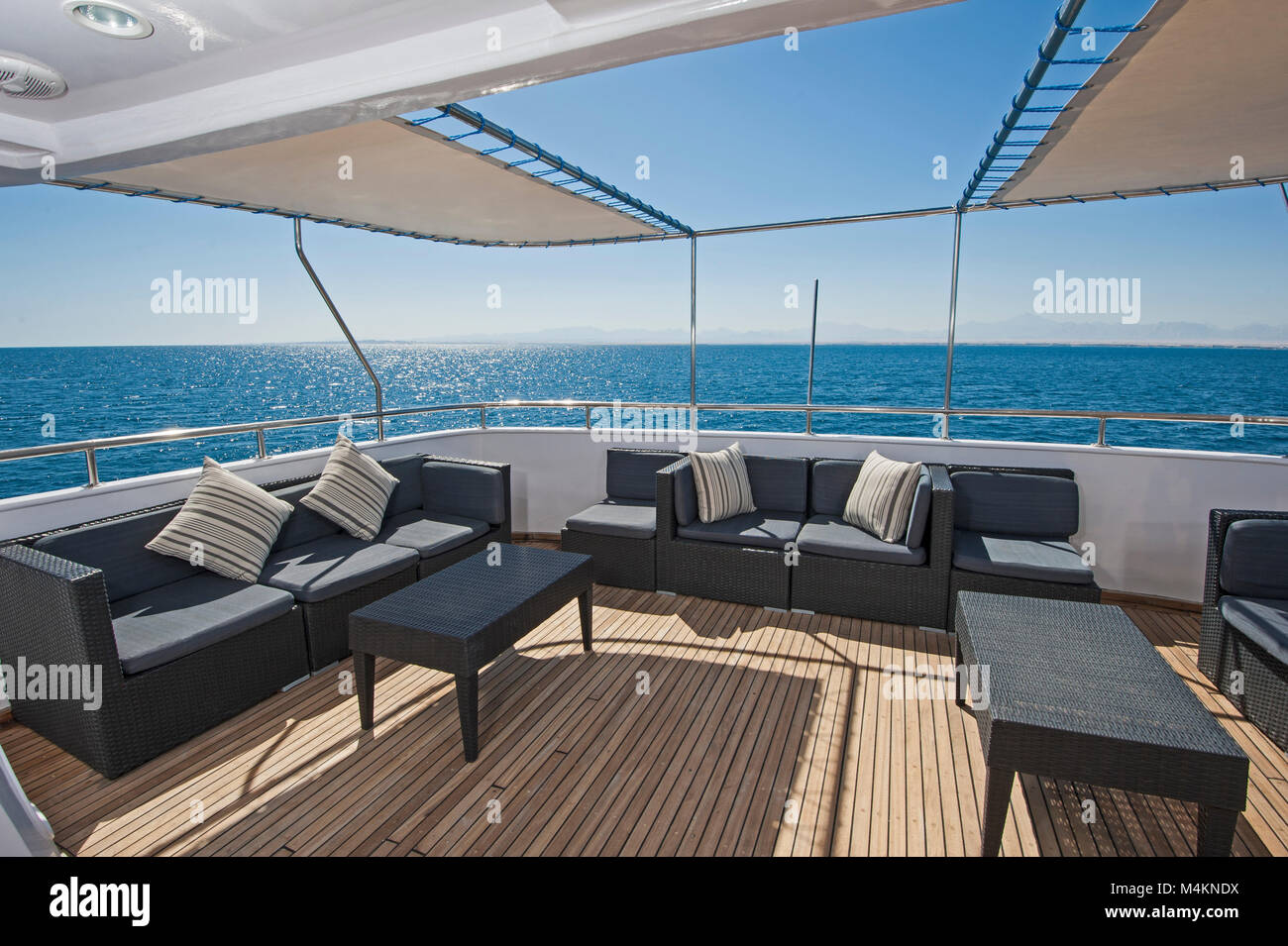 Rear teak deck of a large luxury motor yacht with chairs sofa table and ...