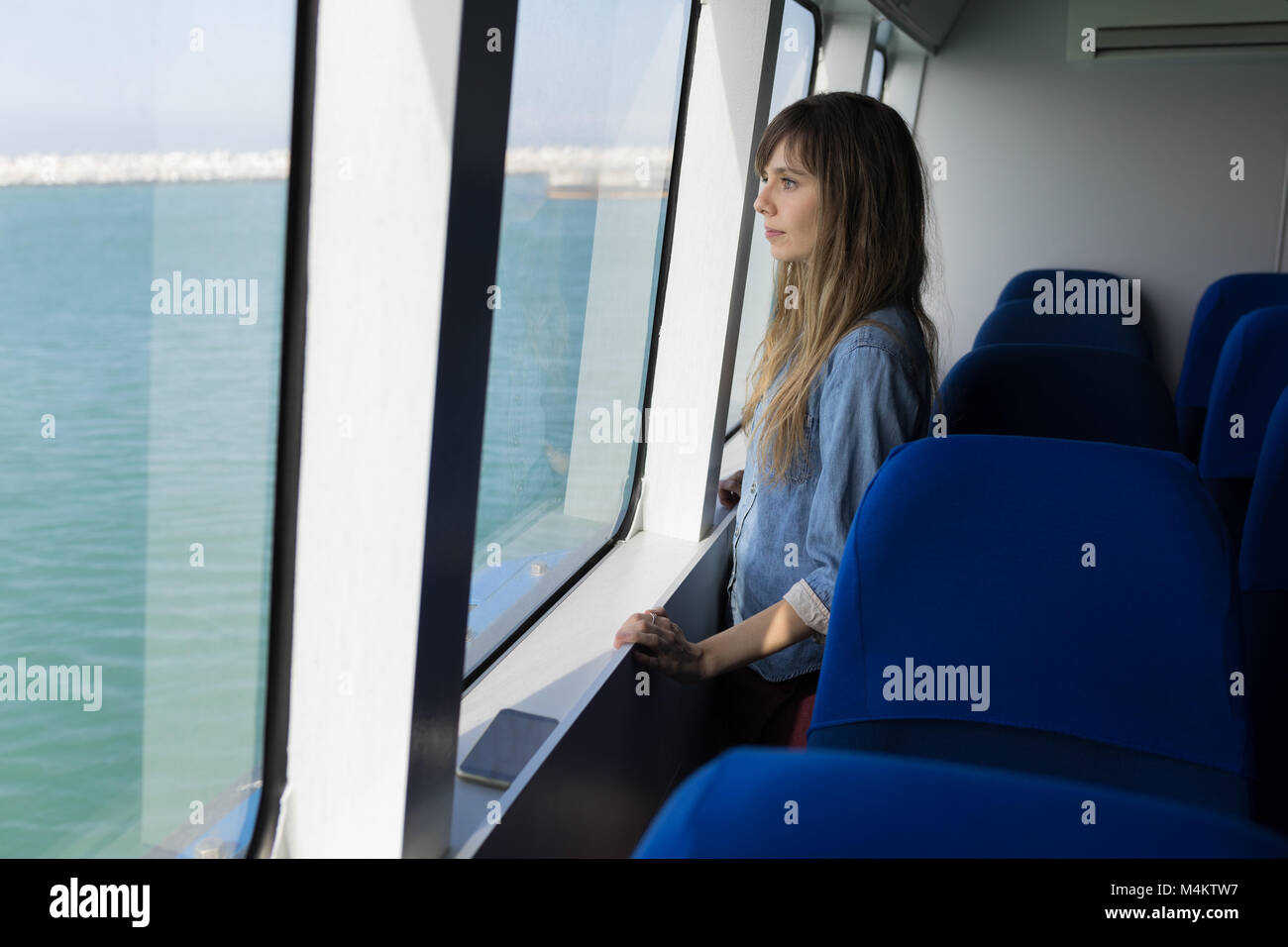 Woman looking through window while sailing in cruise ship Stock Photo ...