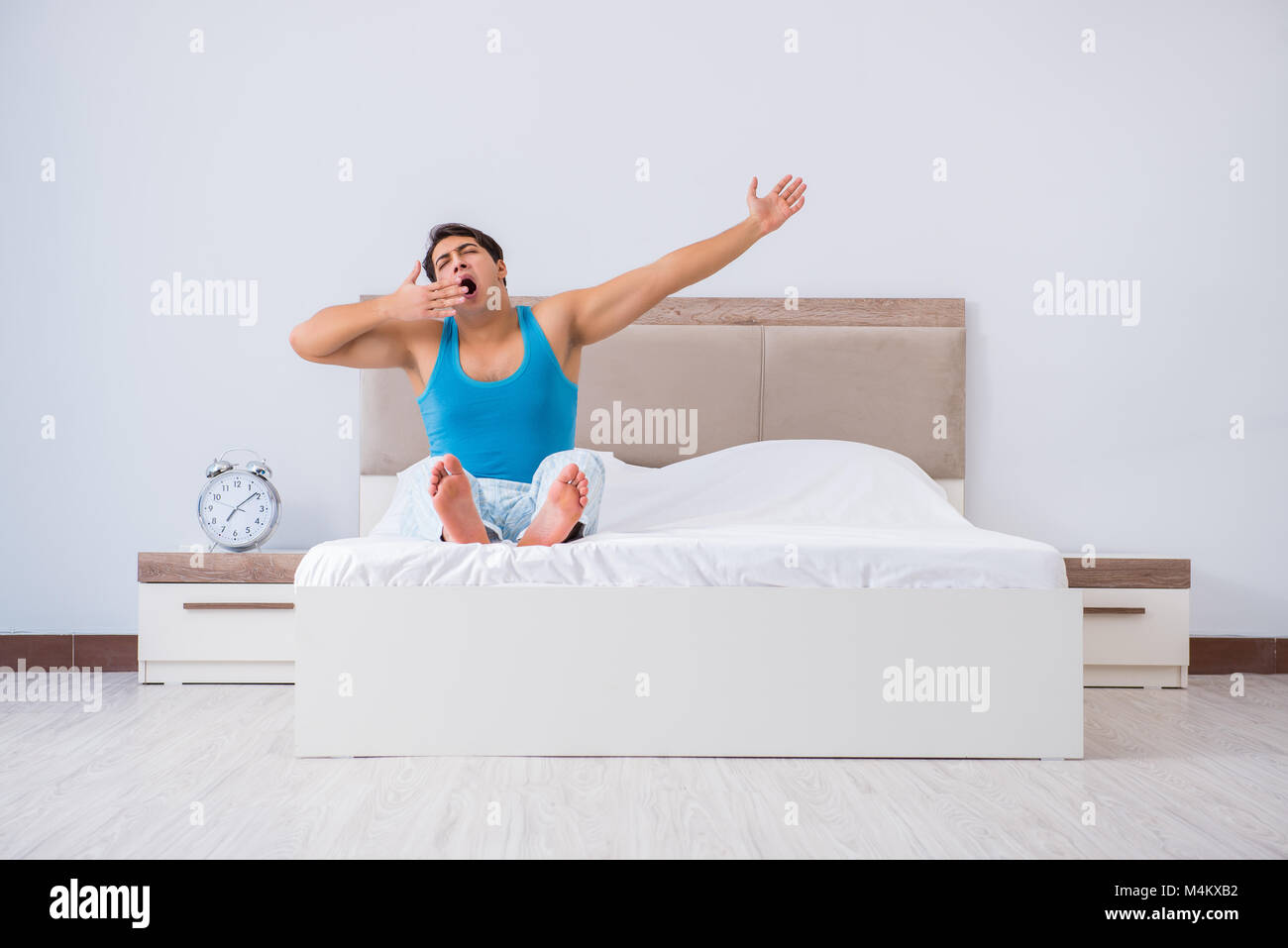 Young man waking up in bed Stock Photo - Alamy
