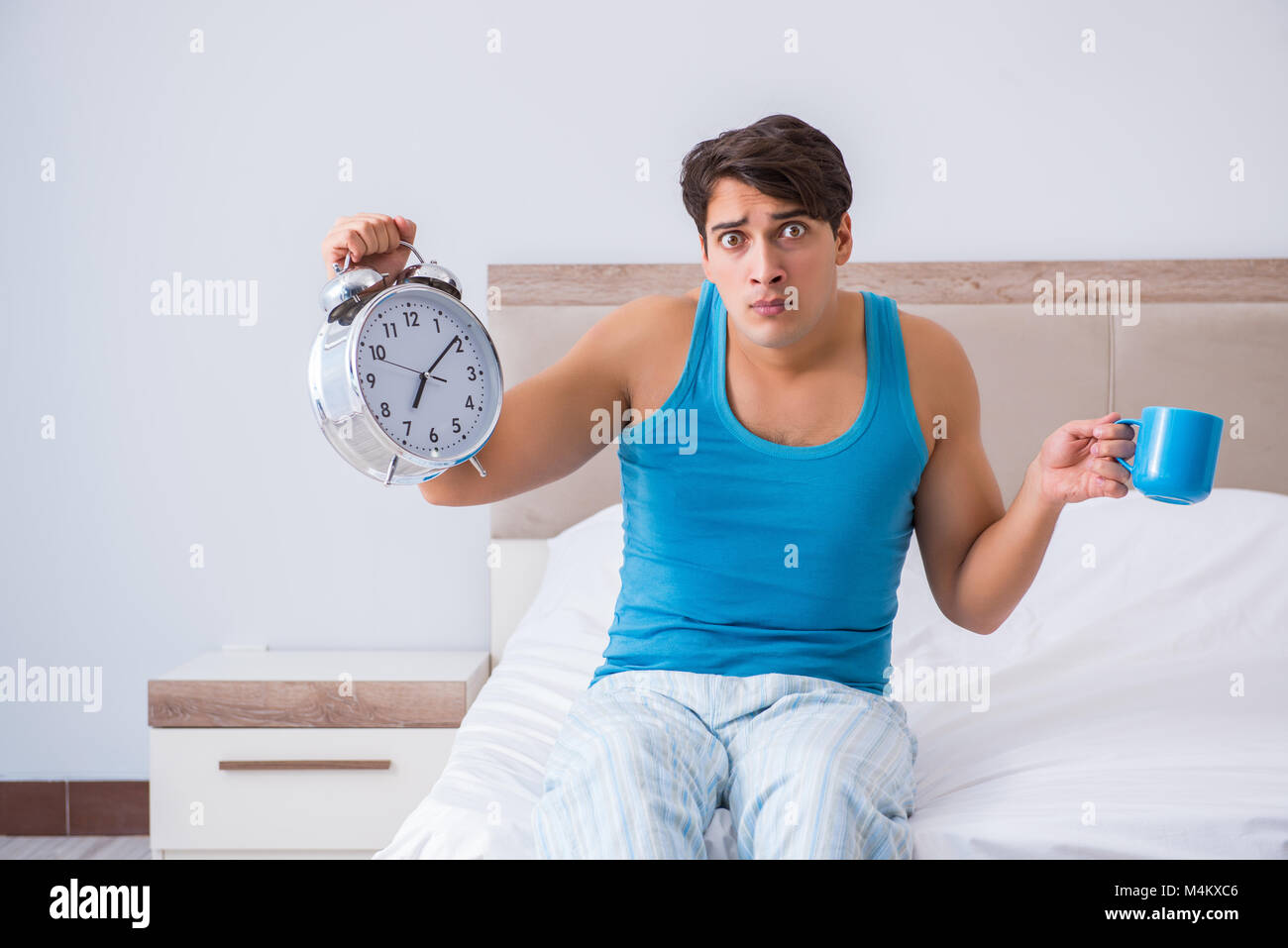 Young man waking up in bed Stock Photo - Alamy