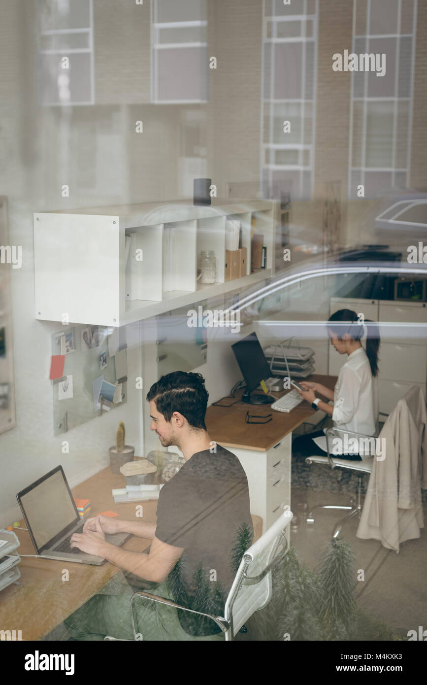 Executives using laptop and mobile phone at desk Stock Photo - Alamy