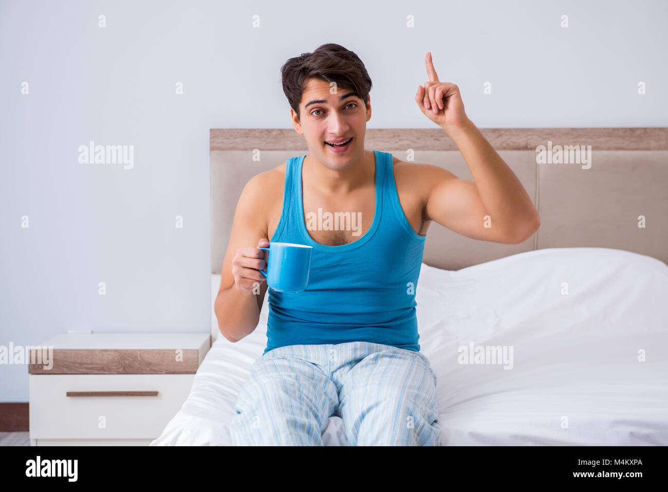 Young man waking up in bed Stock Photo - Alamy