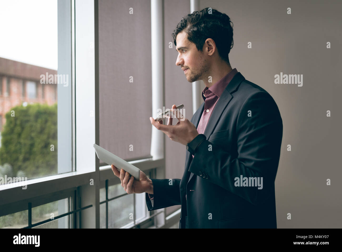 Male executive talking on mobile phone while holding digital tablet ...