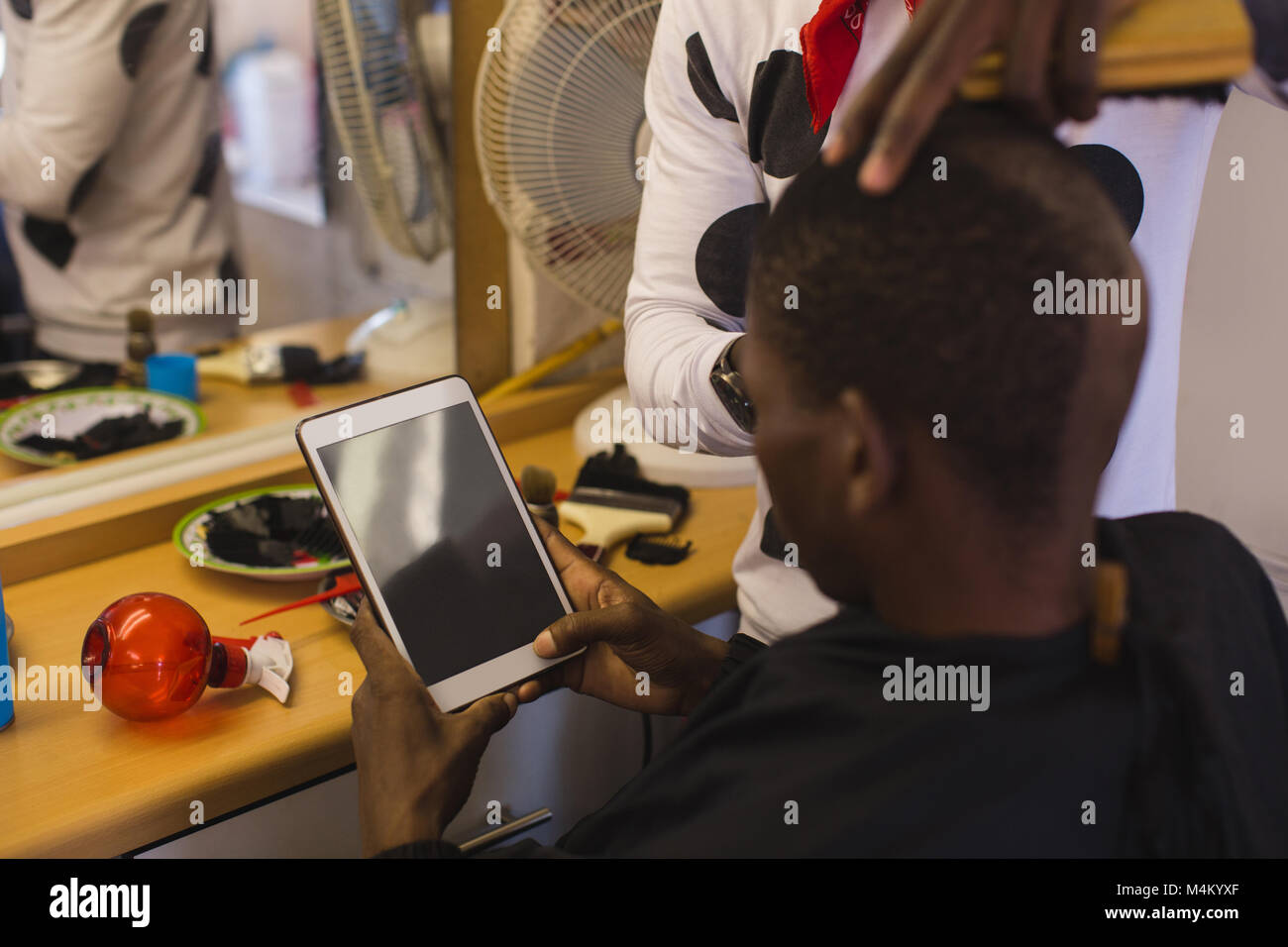 Customer using digital tablet while barber trimming his hair Stock ... Customer using digital tablet while barber trimming his hair Stock ...
