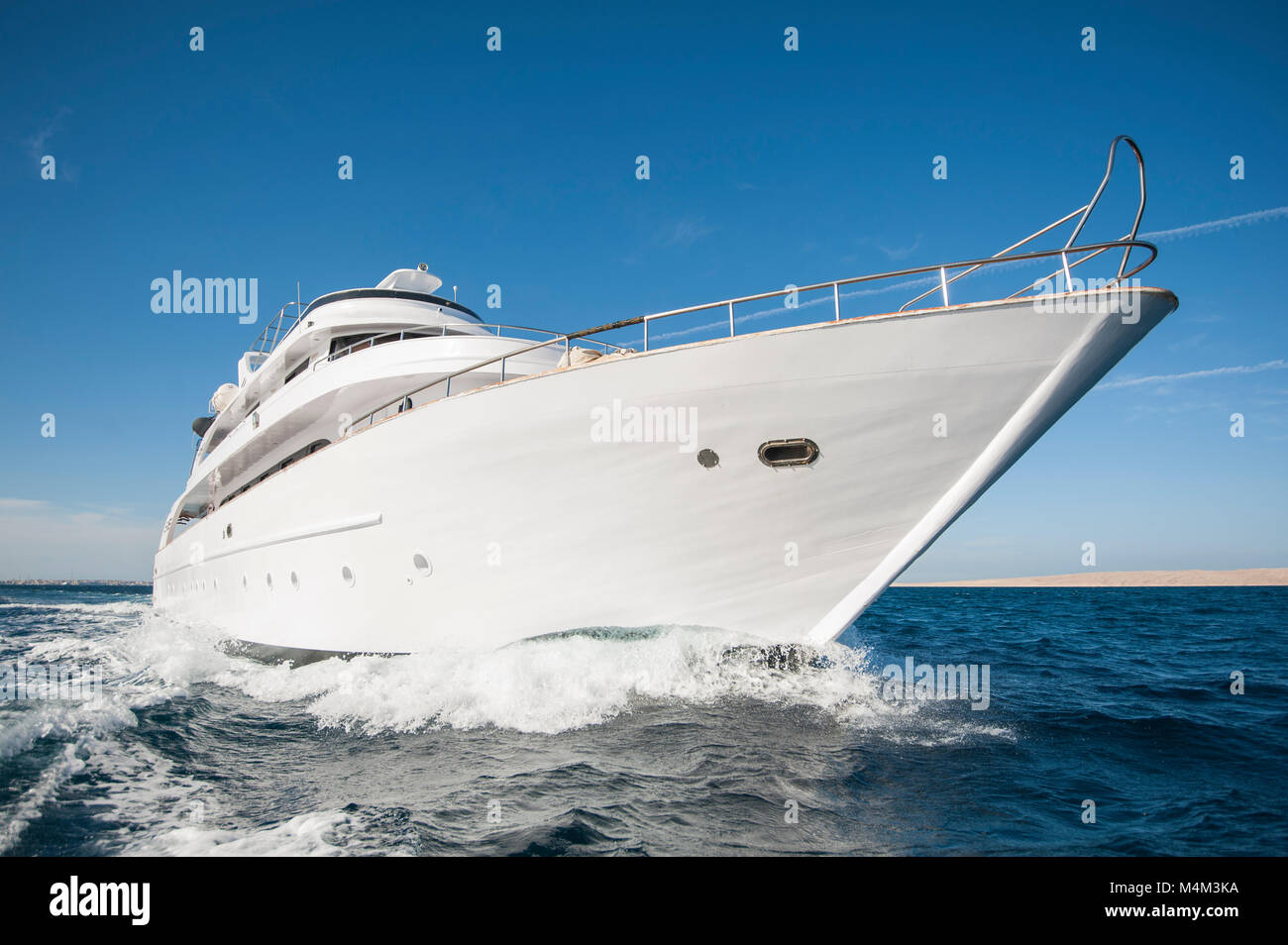 A luxury private motor yacht under way on tropical sea with bow wave ...