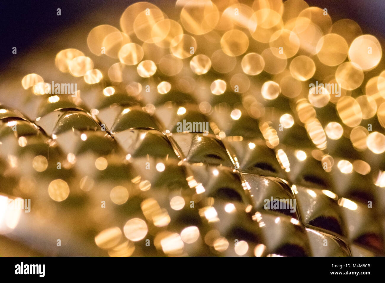 Golden sparkles reflecting from shiny patterned surface. Close up/macro ...