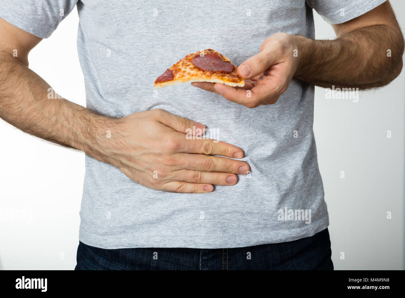 Close-up Of A Man Holds A Slice Of Pizza And Rubs His Belly Stock Photo ...