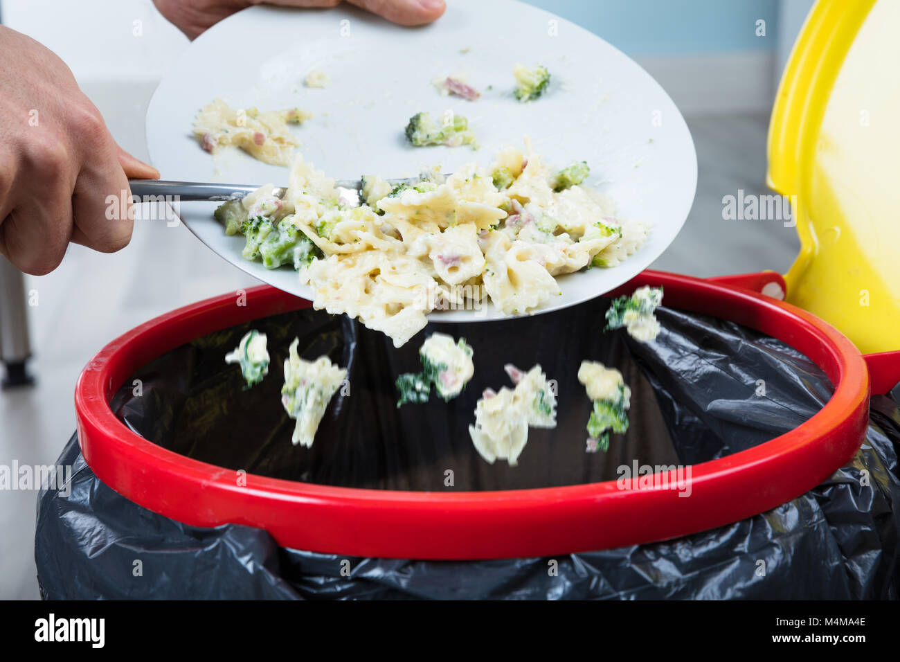 Close-up Of A Person Throwing The Leftover Pasta Into The Trash Bin ...