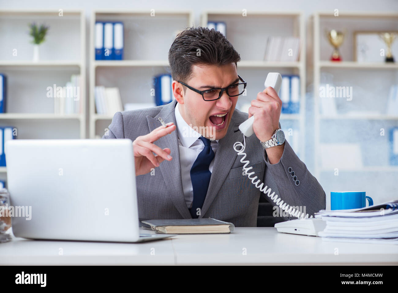 Businessman smoking in office at work Stock Photo - Alamy