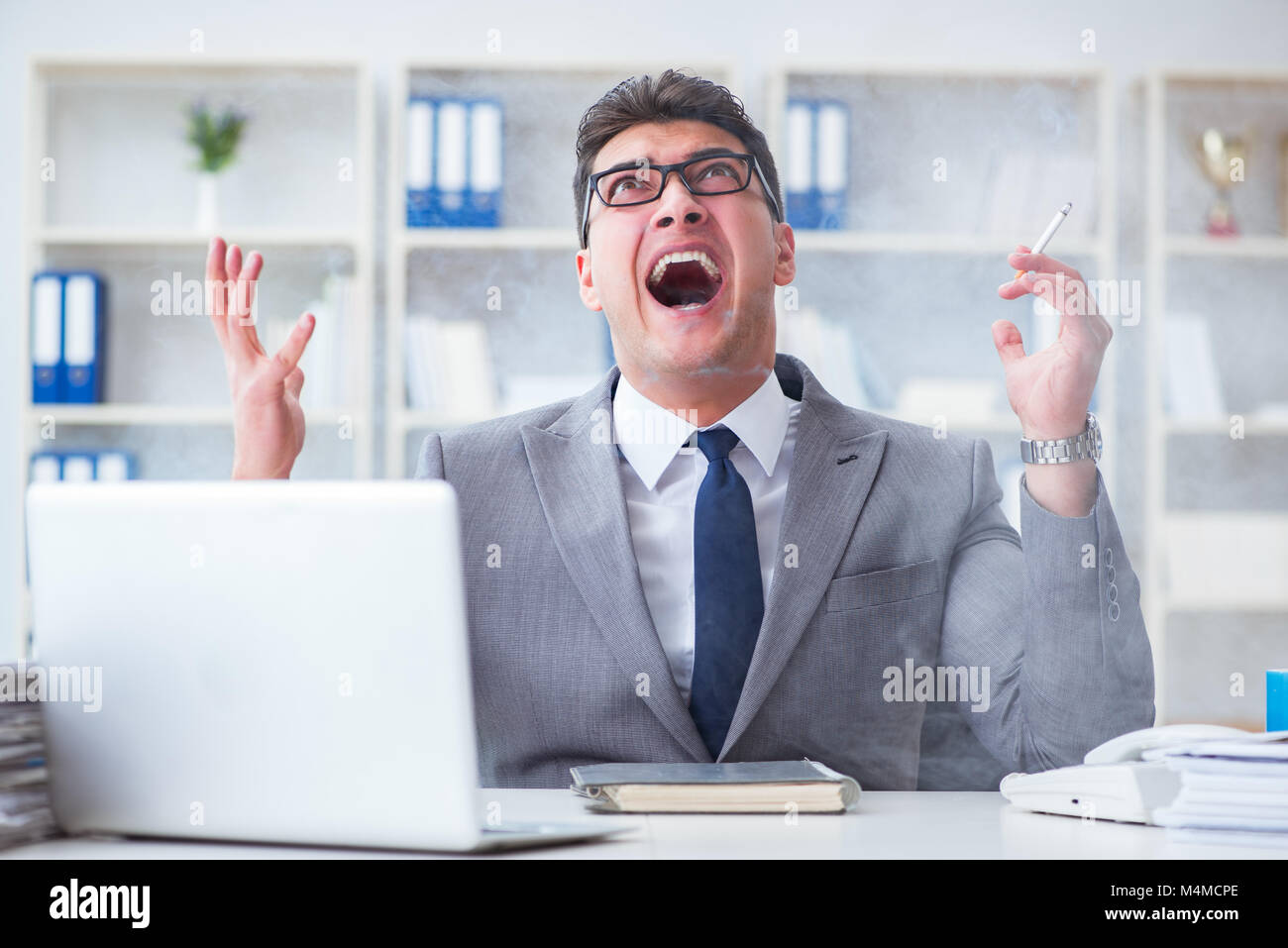 Businessman smoking in office at work Stock Photo - Alamy