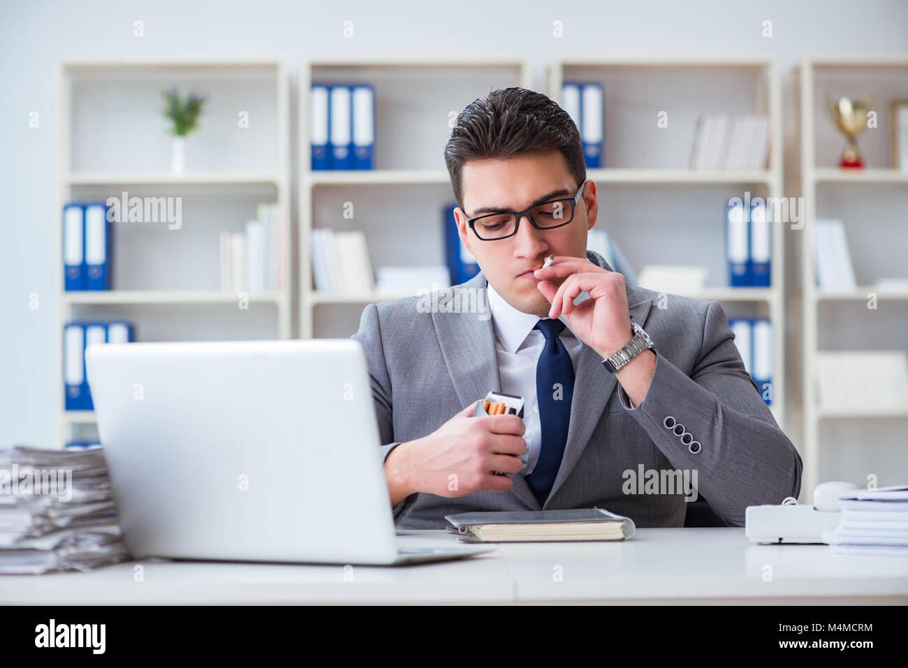 Businessman smoking in office at work Stock Photo - Alamy