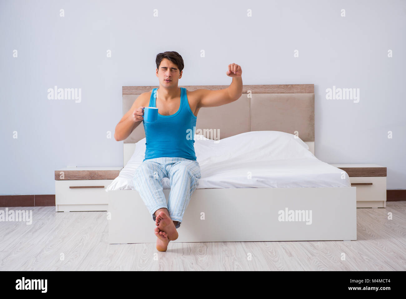 Young man waking up in bed Stock Photo - Alamy