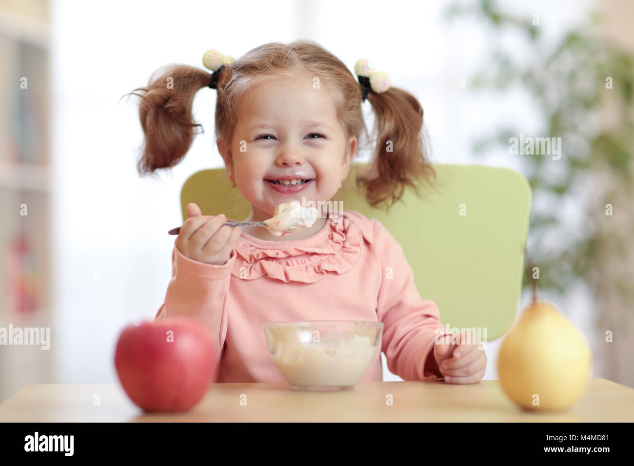 Happy baby eating porridge with spoon Stock Photo - Alamy