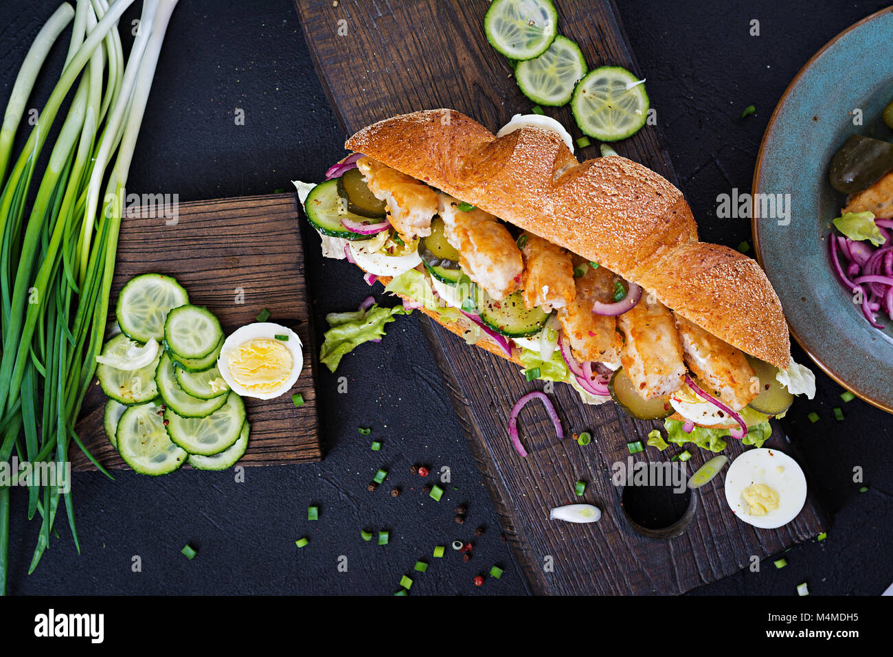 Baguette sandwich with fish, egg, pickled onions and lettuce leaves ...