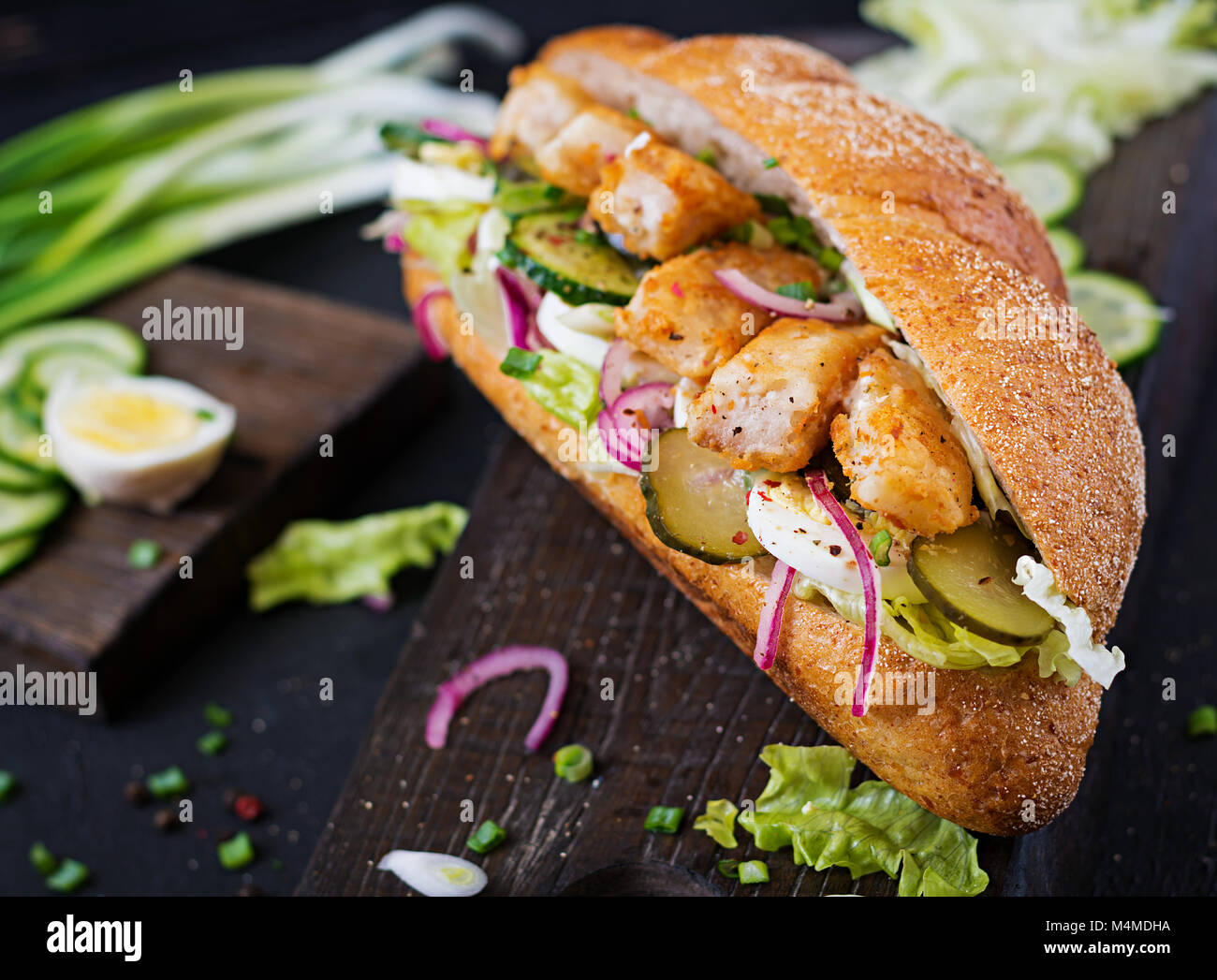 Baguette sandwich with fish, egg, pickled onions and lettuce leaves ...