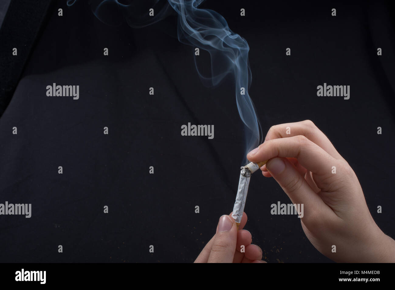 Hand is holding smoking cigarette with smoke around Stock Photo - Alamy