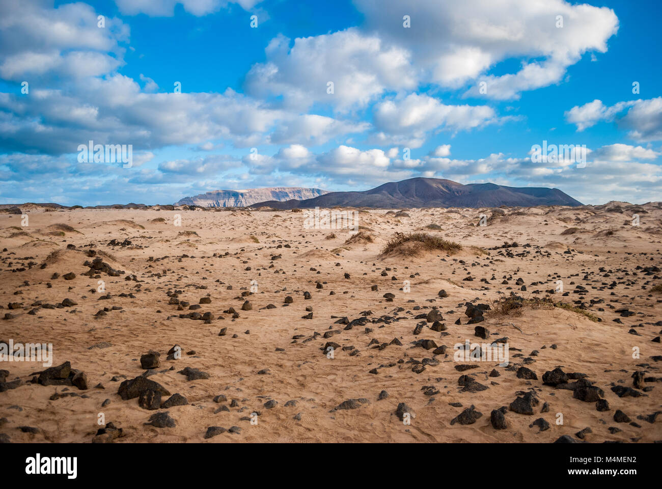 volcanic landscape with mountains in the background and red sand and ...