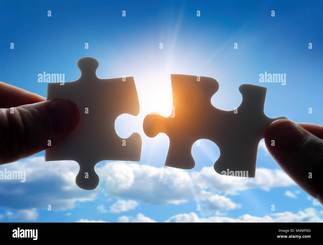 Putting puzzle pieces together on sky background with sunlight Stock ...