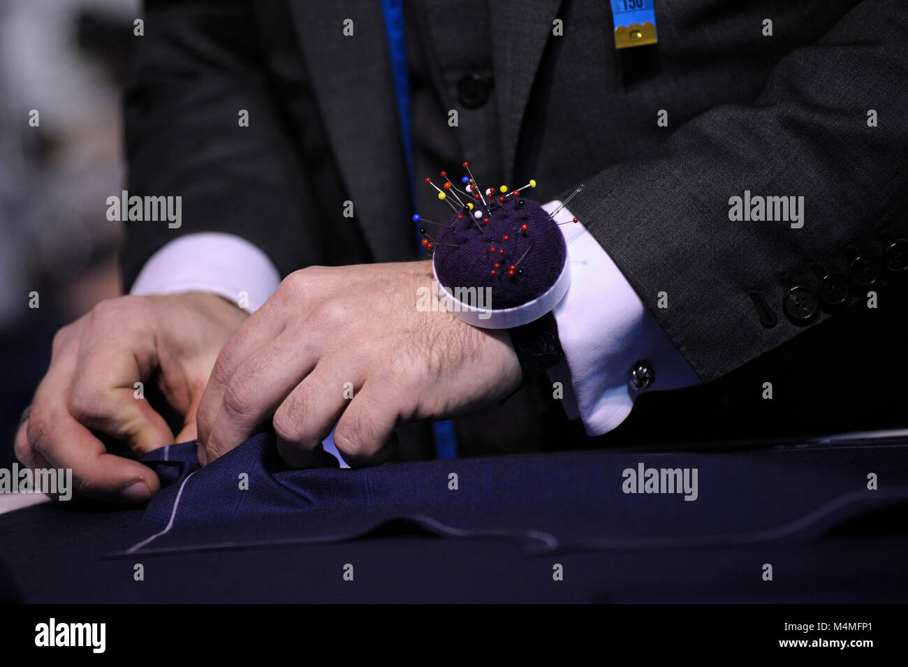 Dressmaker’s hands stitching fabric cloth on a tailor cutting table ...
