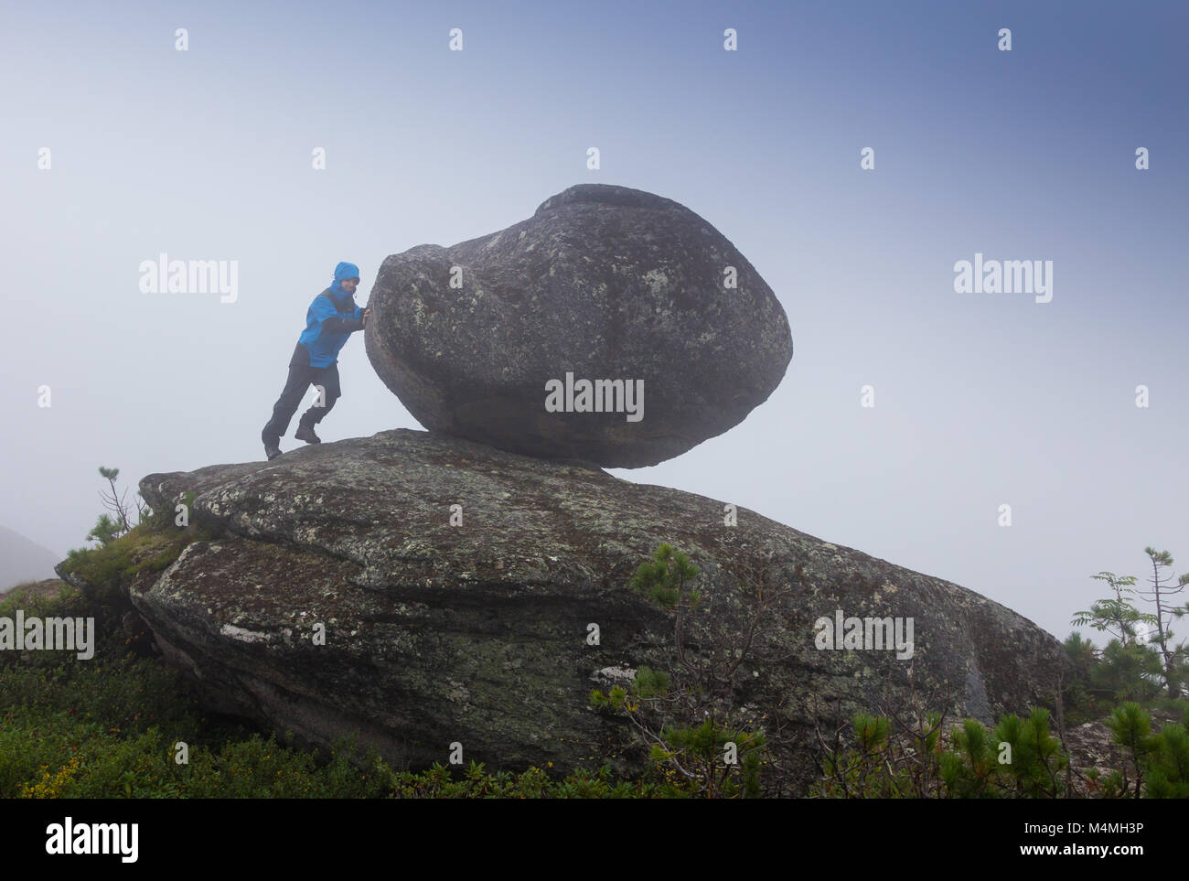 Man tries to move the stone hanging in the mountains in a fog Stock ...
