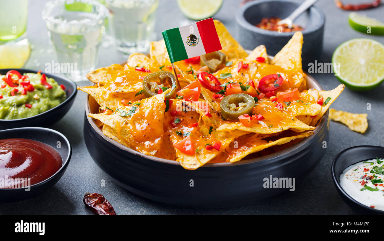 Nachos chips with Mexican flag and dips variety in black bowl. Grey ...