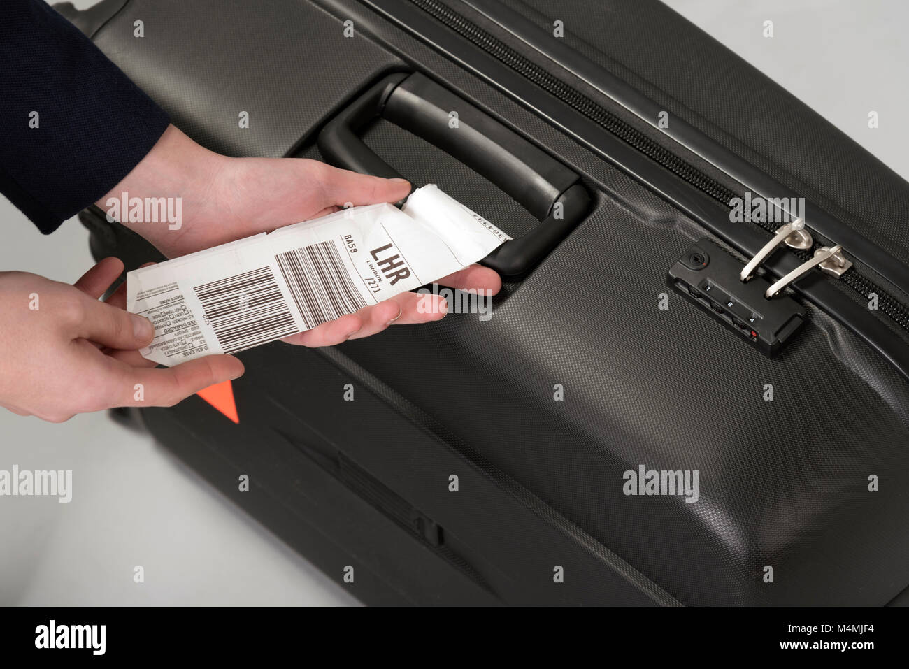 Airline luggage security tag being attached to a travellers black ...