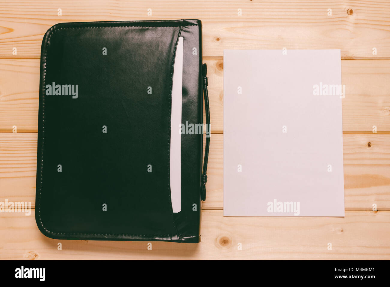 black leather briefcase with papers and blank white sheet of paper ...