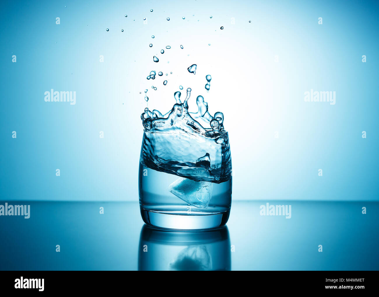 Pure water splashing out of glass on blue background Stock Photo - Alamy