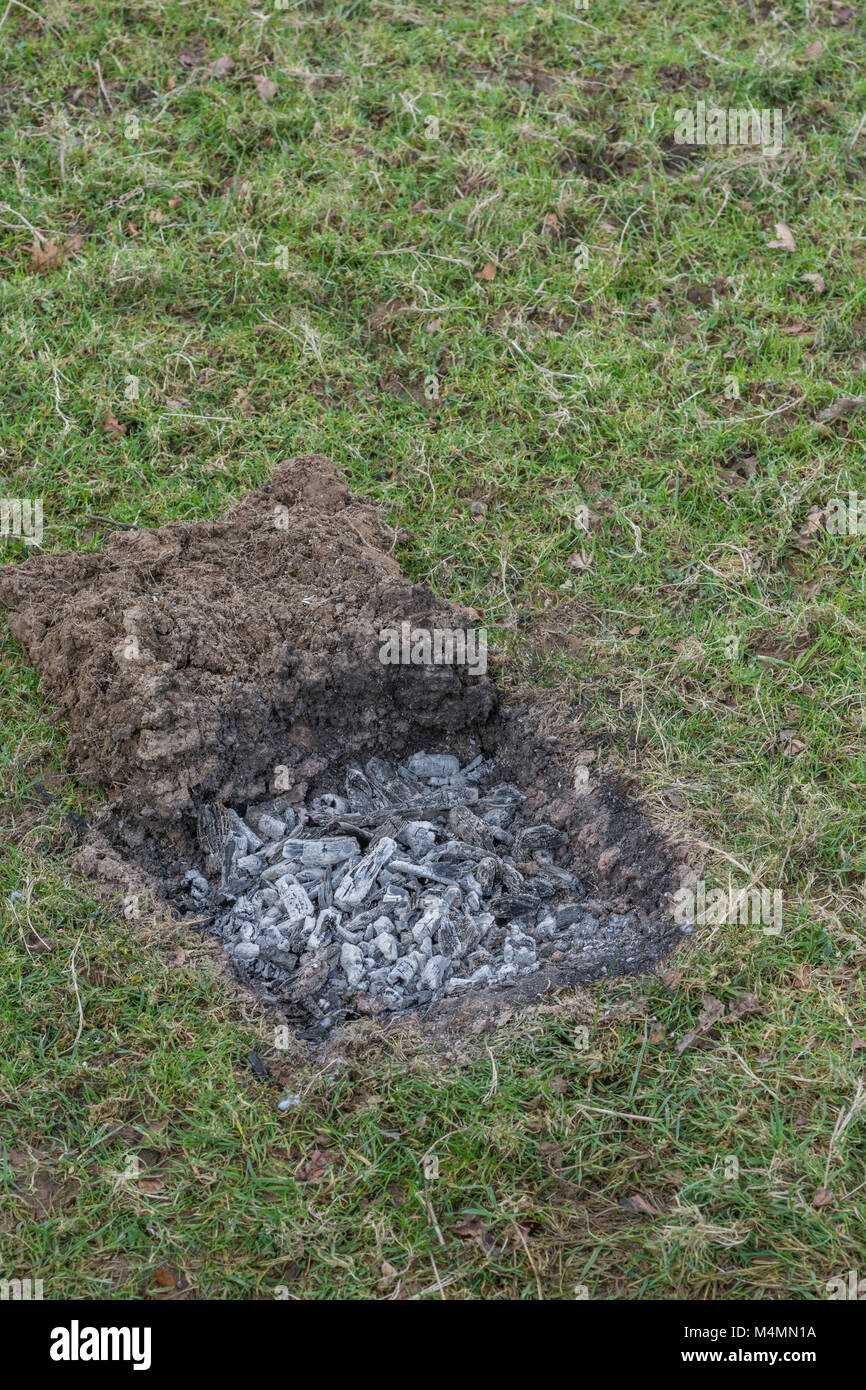 Grass turf cut away to form a shallow pit for a covert survival fire ...