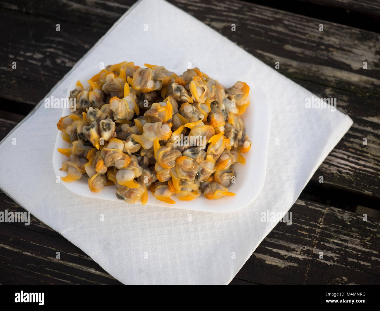 A takeaway plate of Cockles from a seafood stall on an old wooden table ...