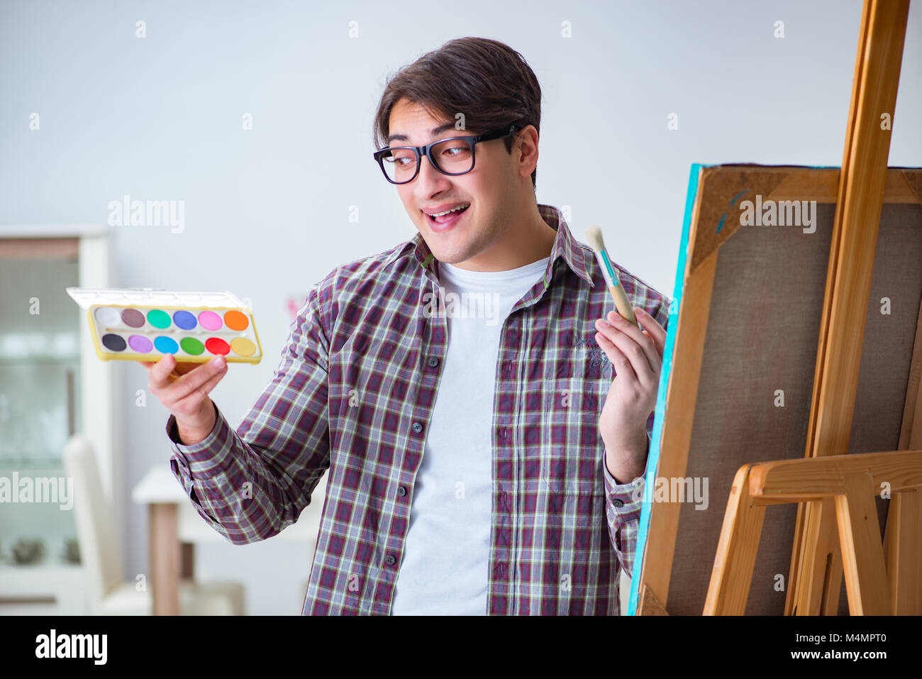 Young male artist drawing pictures in bright studio Stock Photo - Alamy