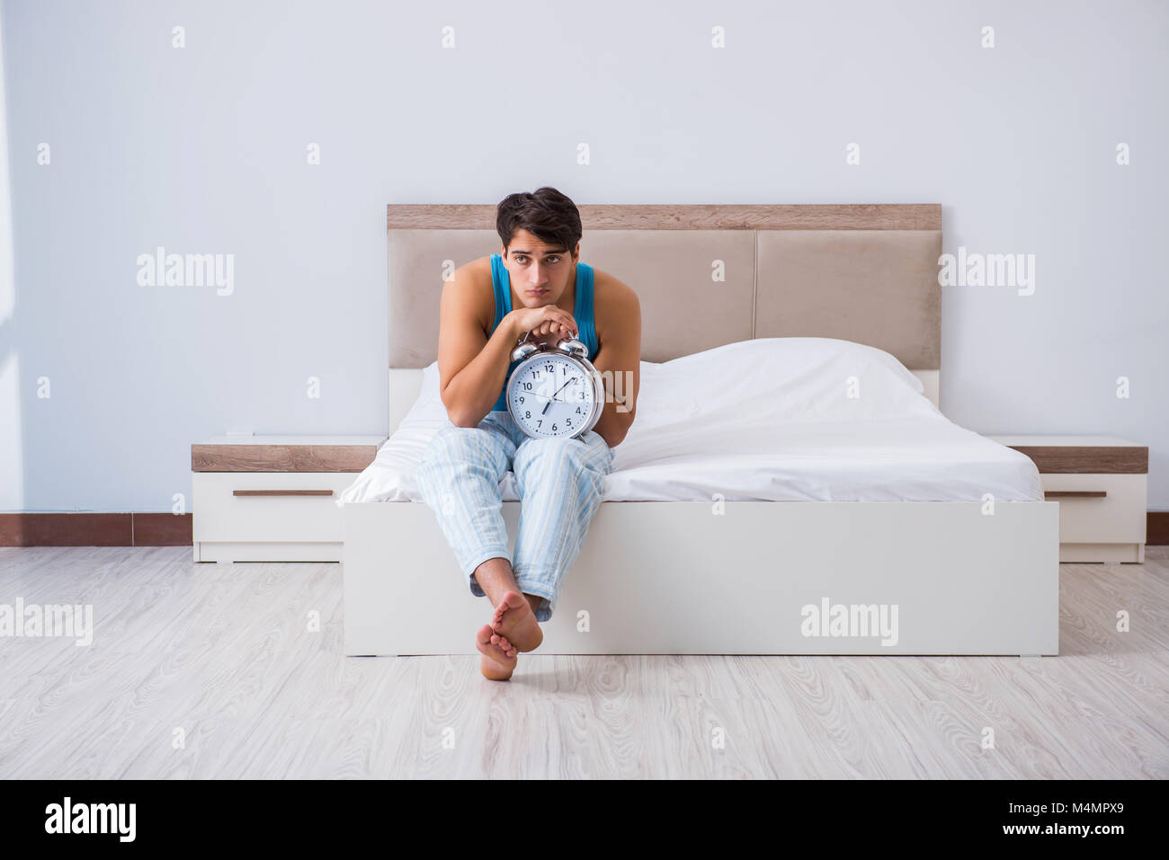 Young man waking up in bed Stock Photo - Alamy
