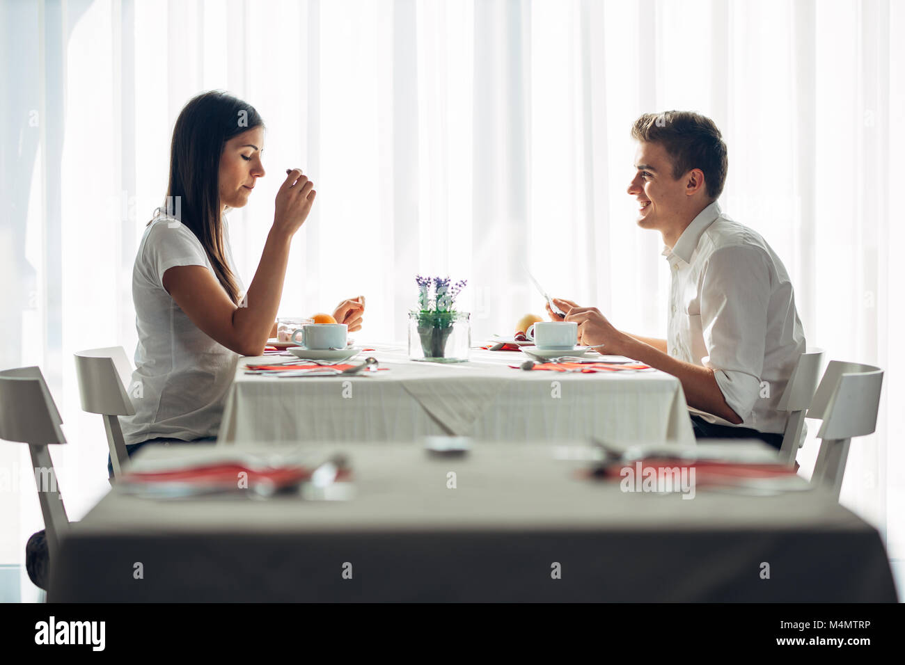 Two casual young adults having a conversation over a meal.Formal ...