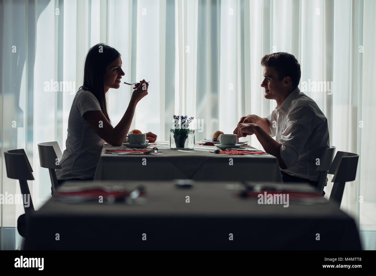 Two casual young adults having a conversation over a meal.Formal ...