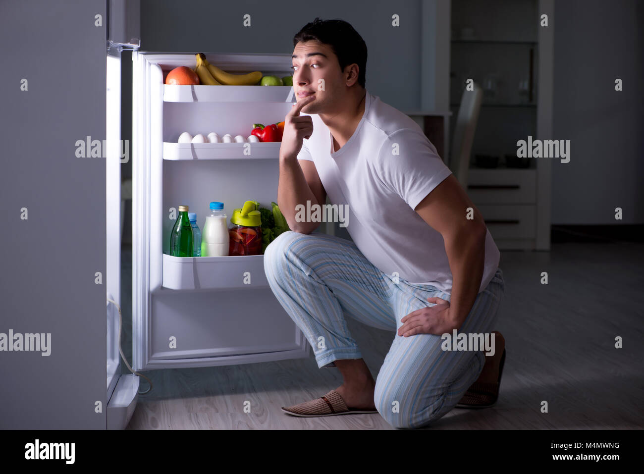 Man at the fridge eating at night Stock Photo - Alamy