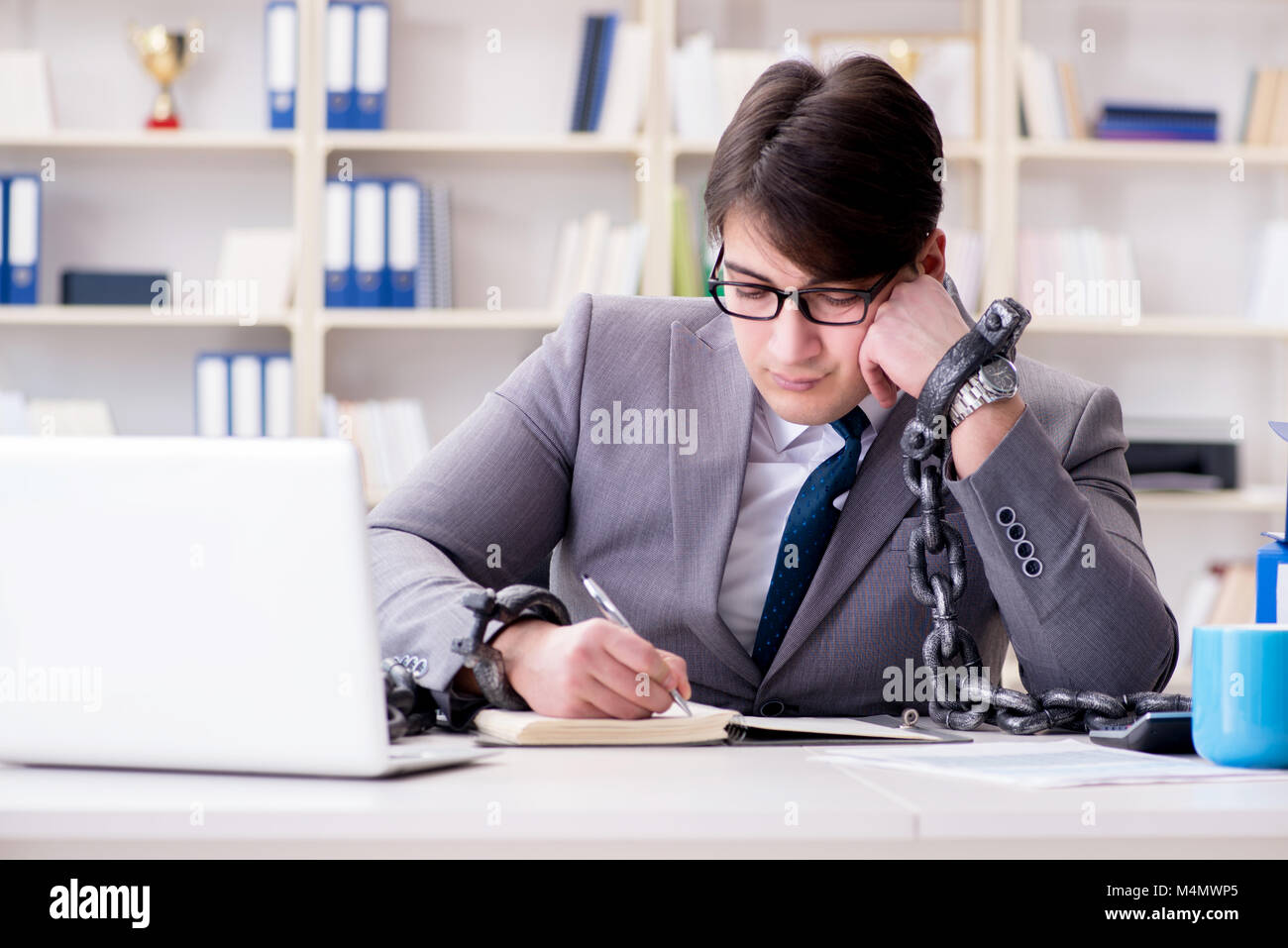 Businessman tied with chains to his work Stock Photo - Alamy
