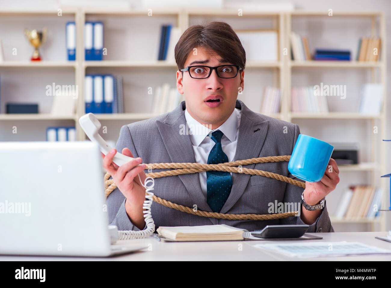 Businessman tied up with rope in office Stock Photo - Alamy