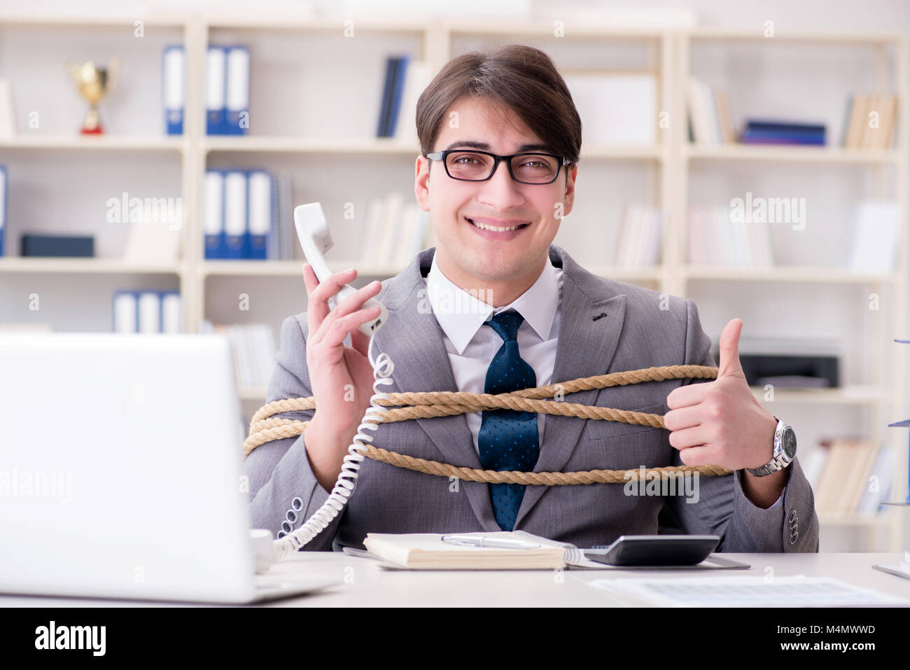 Businessman tied up with rope in office Stock Photo - Alamy