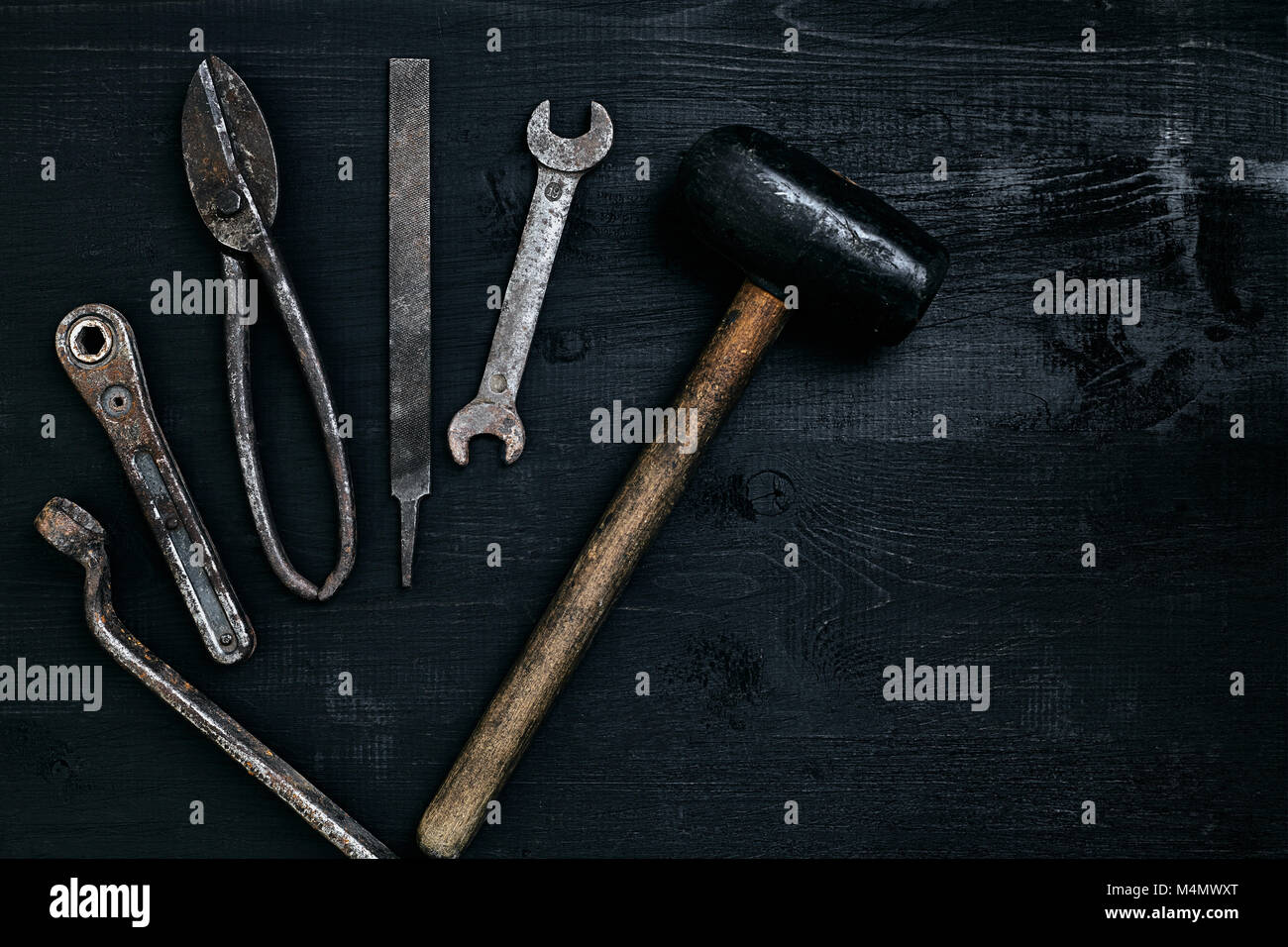 Old, rusty tools lying on a black wooden table. Hammer, chisel, metal ...