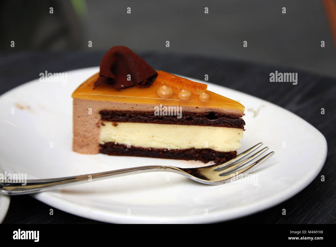 A slice of chocolate orange mousse cake on plate with fork at cafe ...
