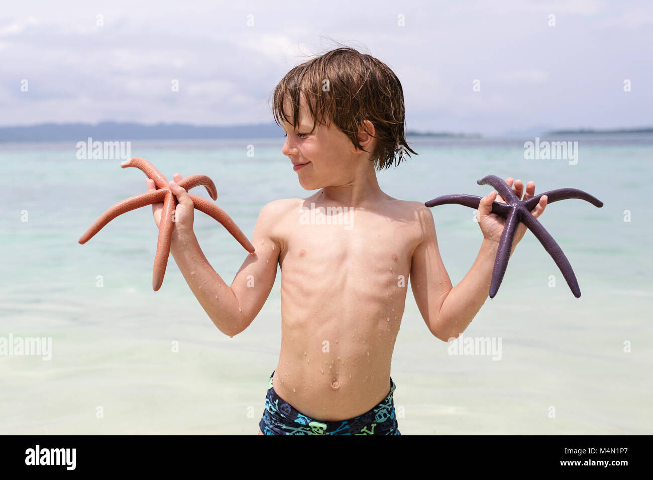 Happy young boy holding two starfish in his hands Stock Photo - Alamy
