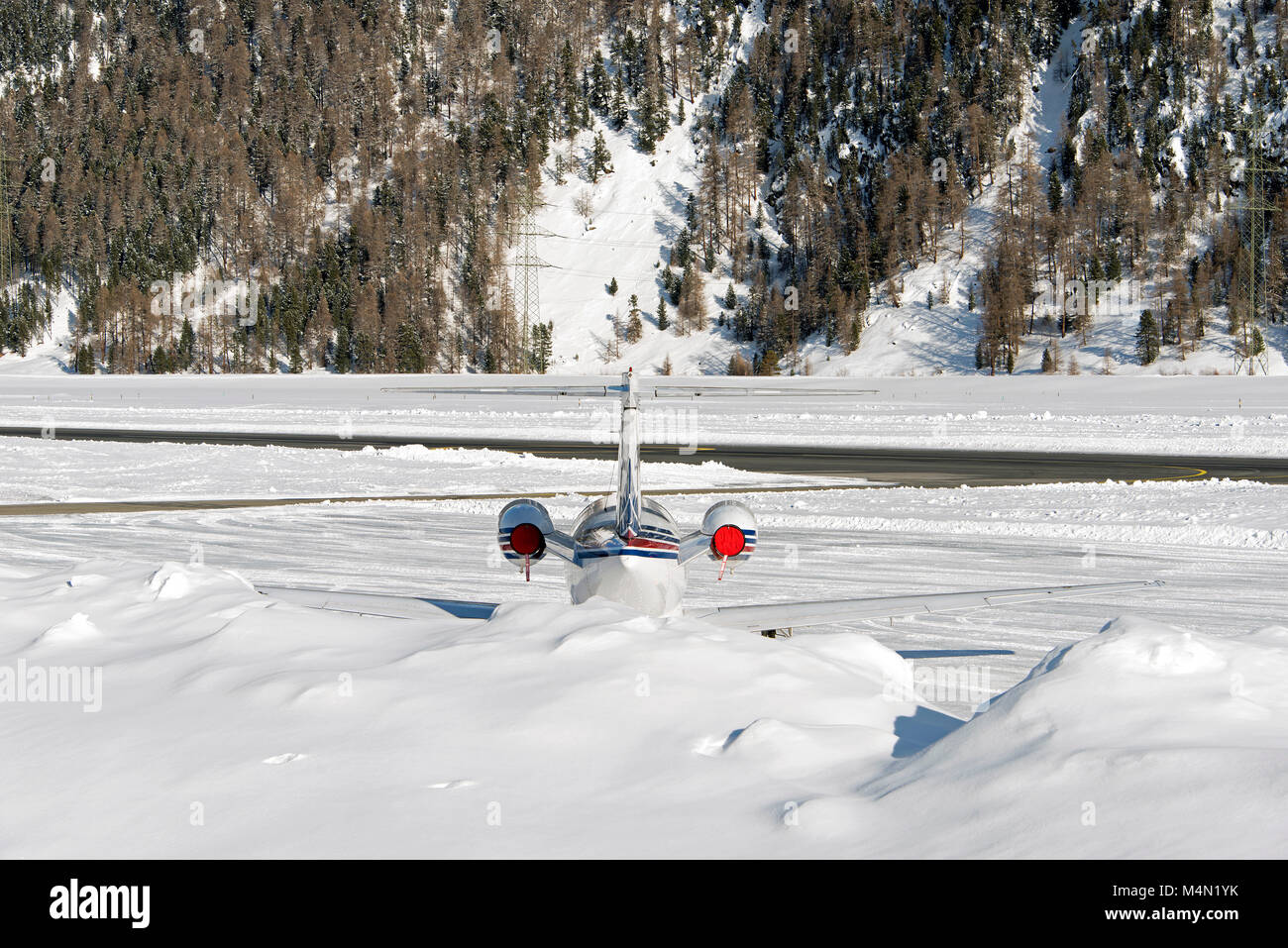 Rear view of a private jet in the snow covered airport in the alps ...