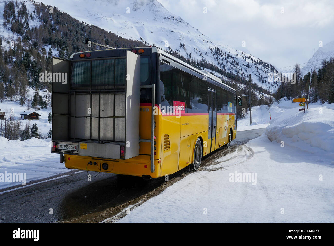 Swiss Post bus driving on a snowy mountain road, Val d'Herens, Valais ...