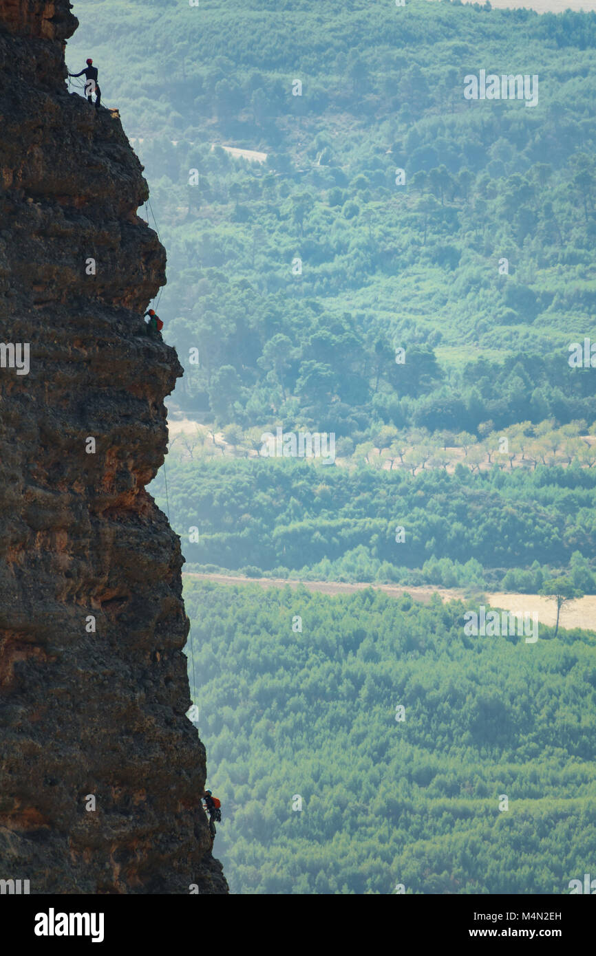 Climbers hanging by a cliff edge against land, vertical composition ...