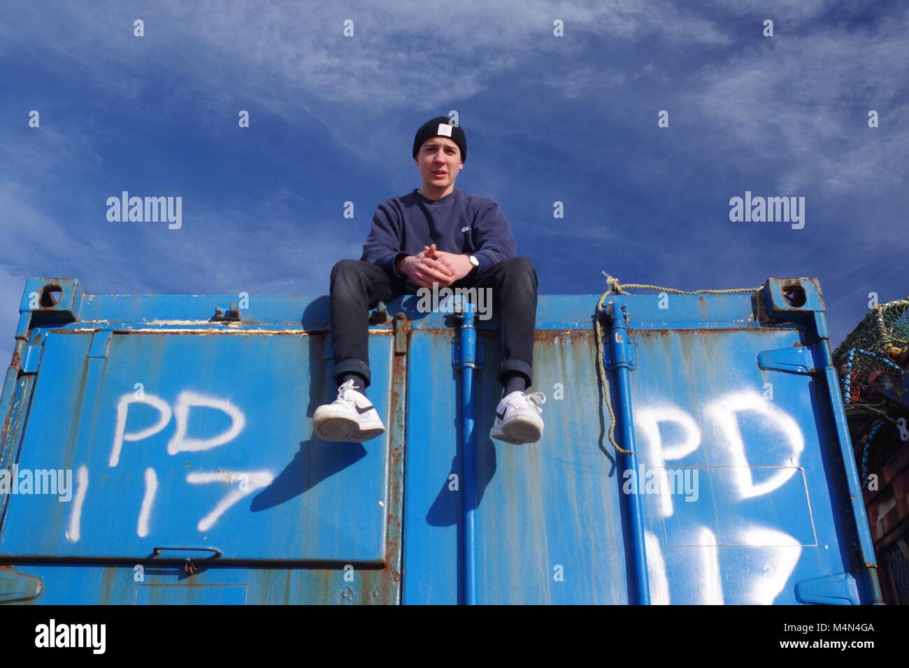 Young Man Sitting Atop an Old Blue Shipping Container at Cruden Bay ...