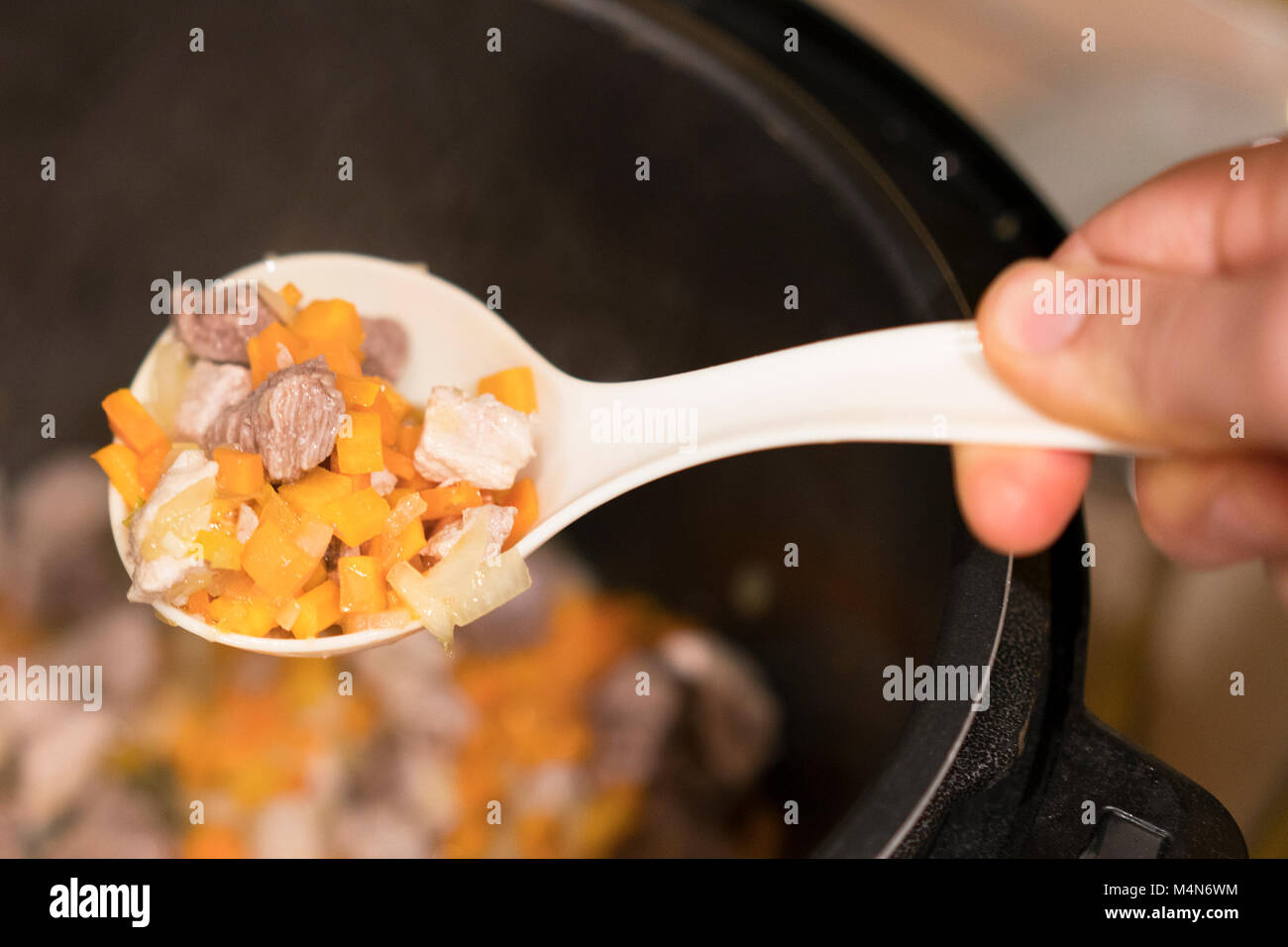 Cooked meat with vegetables in a cooked white spoon on a steam ...
