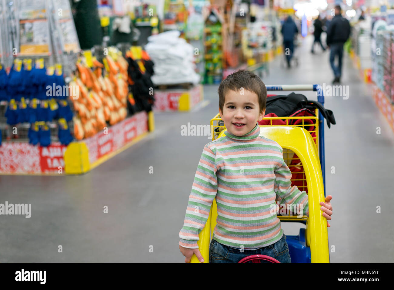 The boy 4 years leaned out of the children's cart in the building store ...