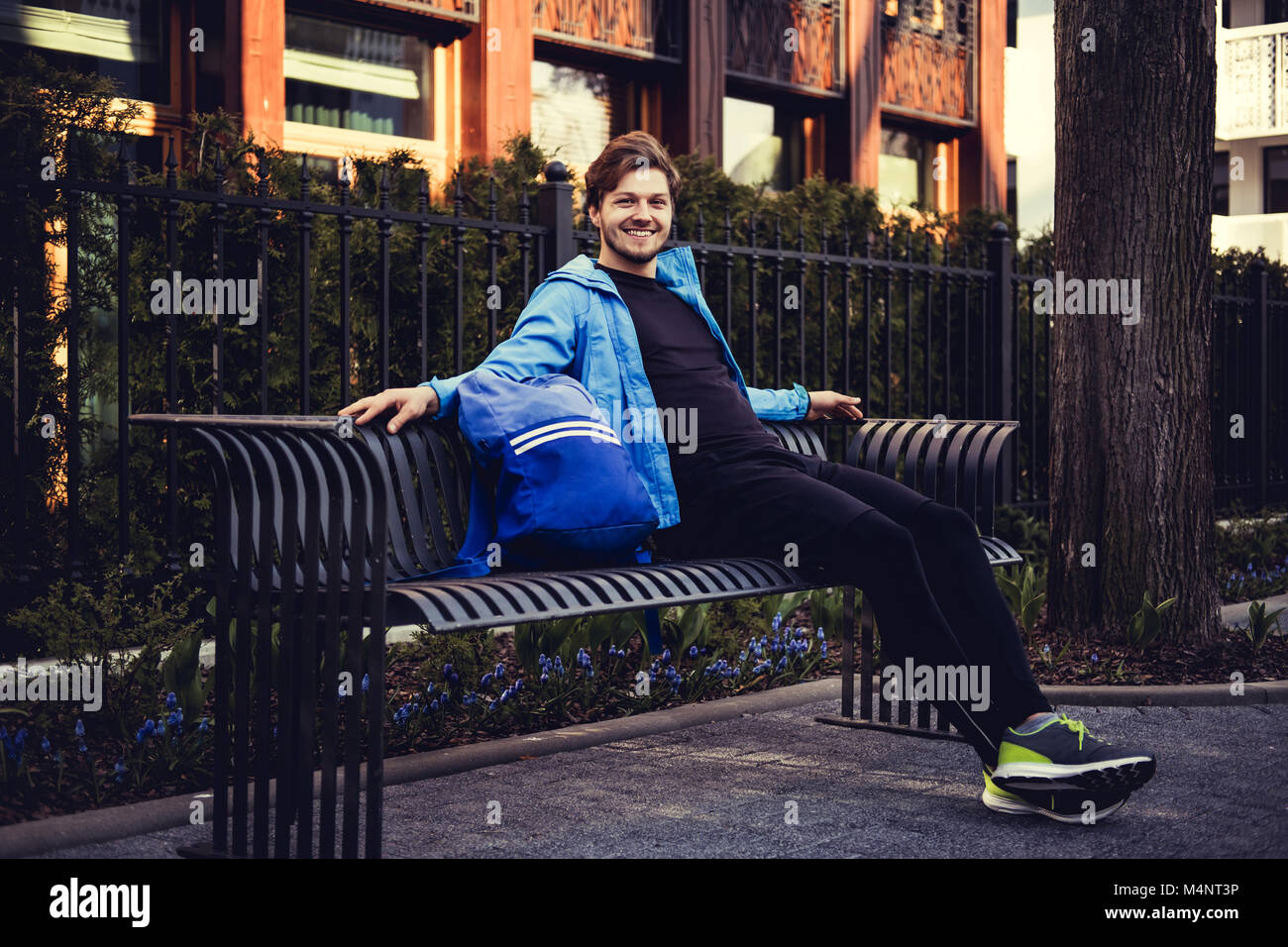 Smiling guy in a sportswear sitting on a bench Stock Photo - Alamy