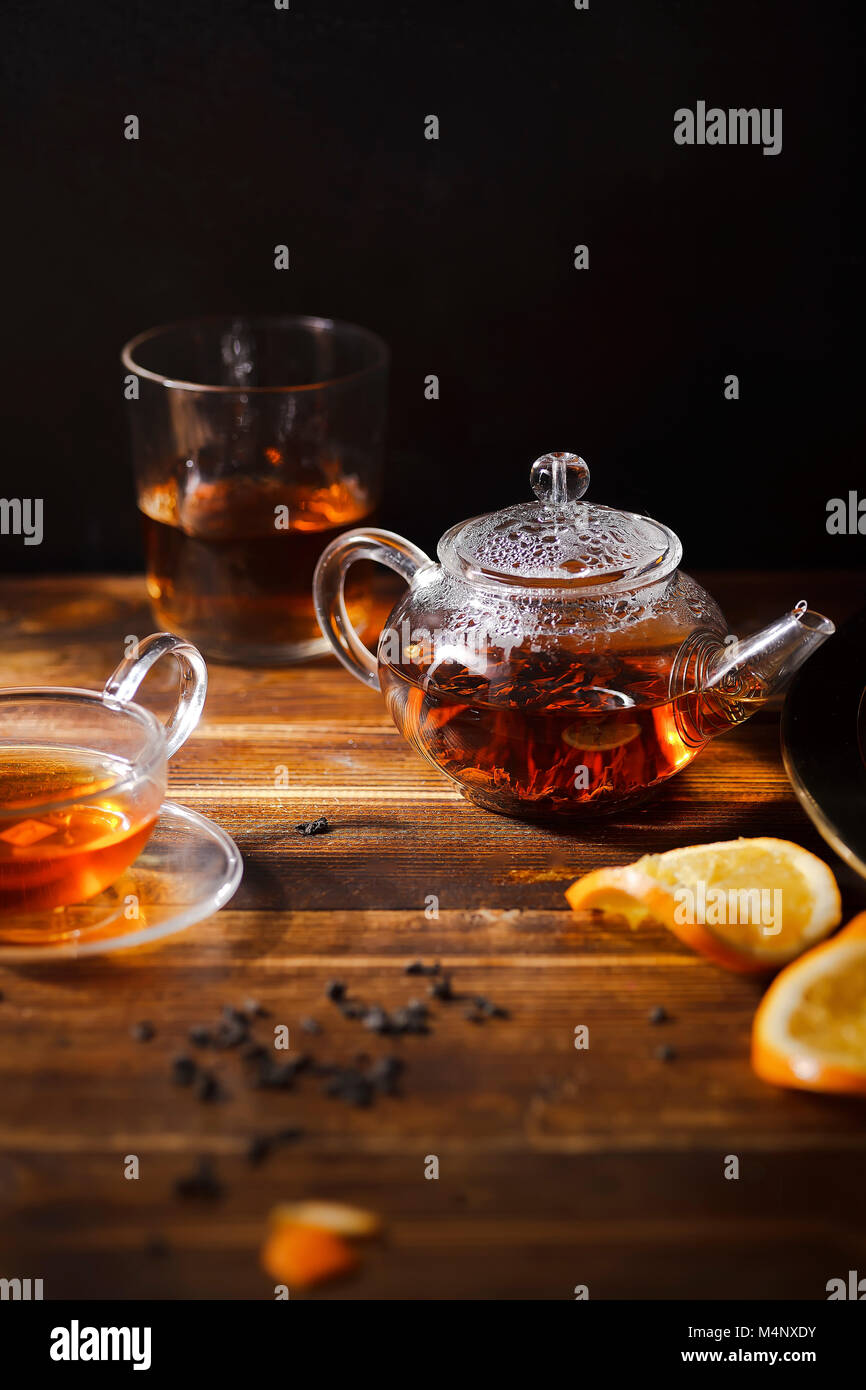 Small glass teapot with hot black tea, cup, glasses, squeezed orange ...