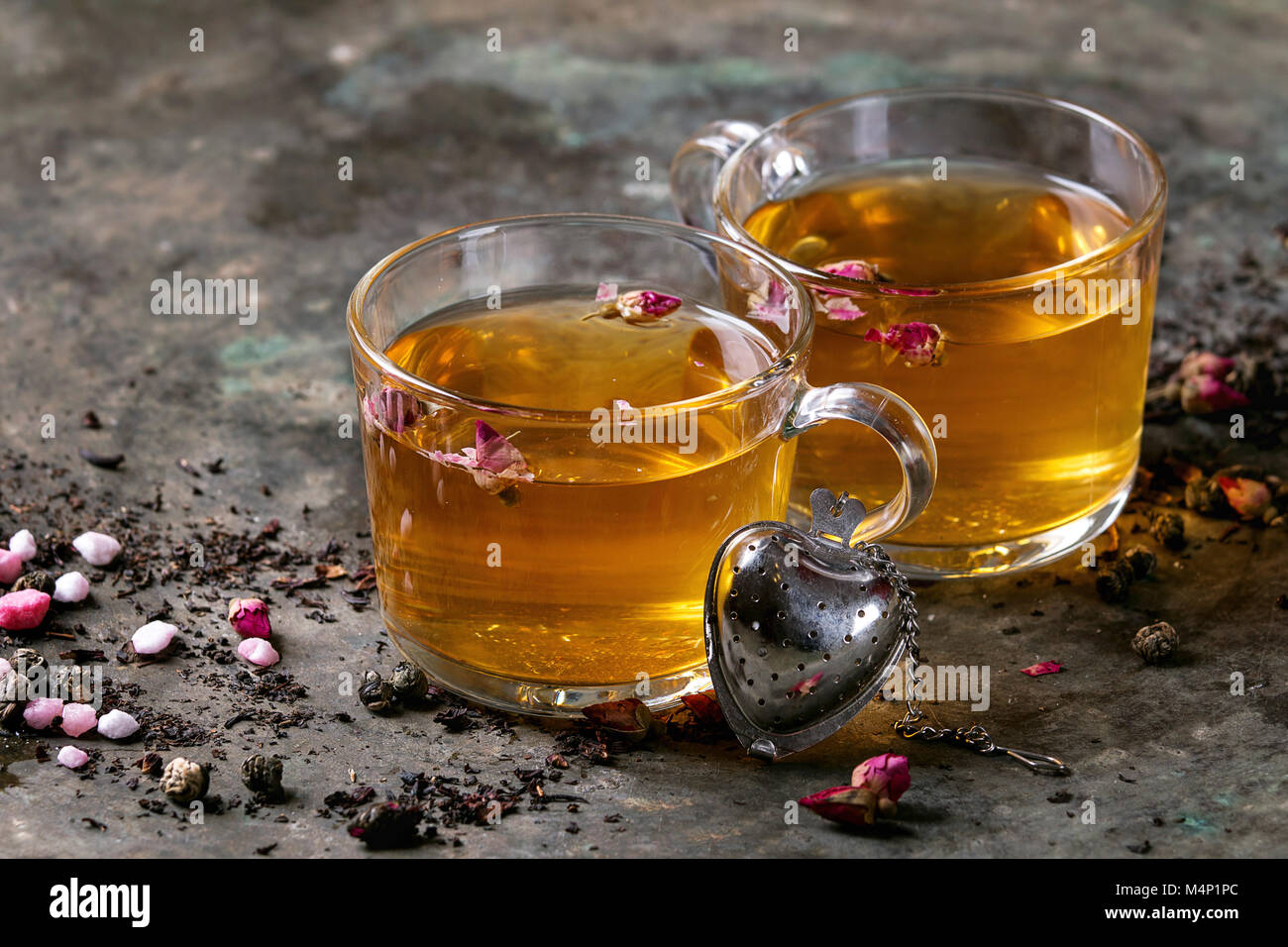 Two glasses of hot tea, rose buds, heart shaped tea strainer, pink ...